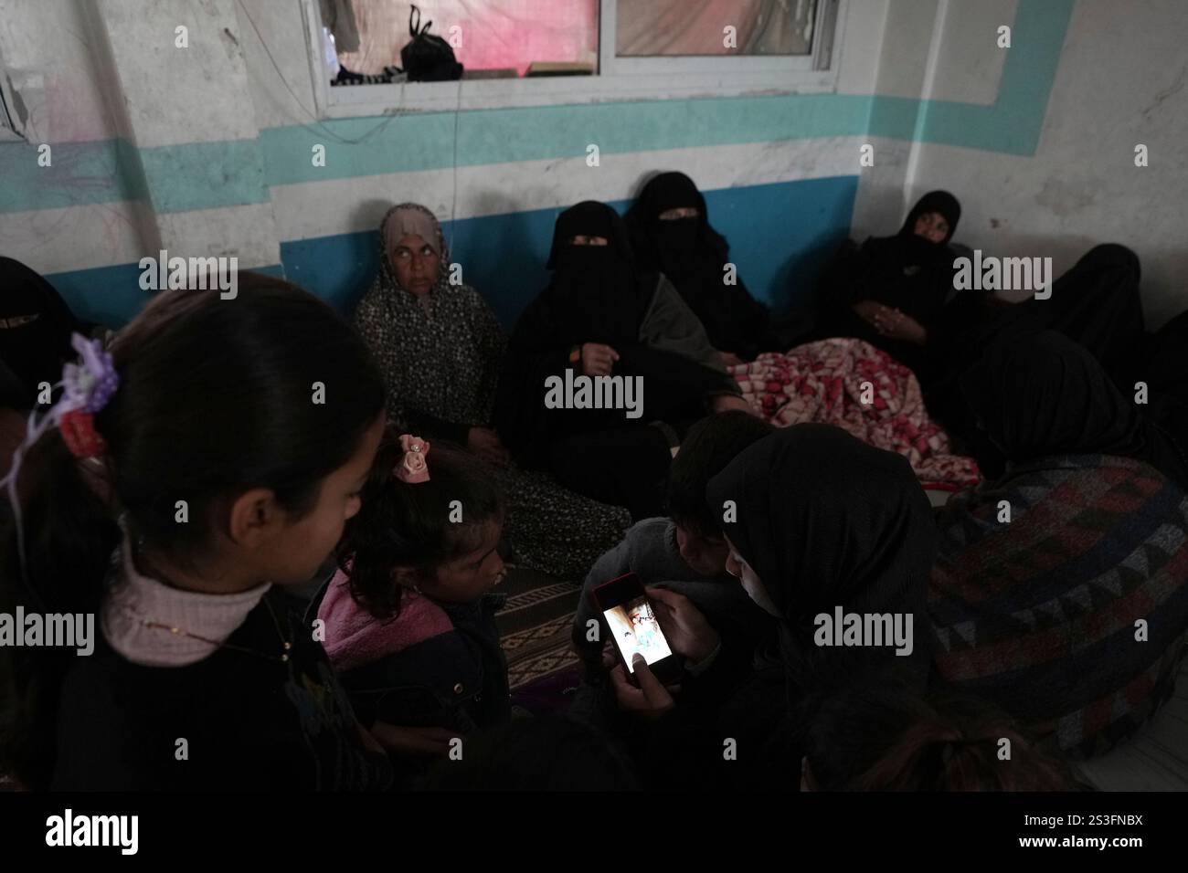 Malak Abu Awad scrolls through pictures of her relatives who were ...