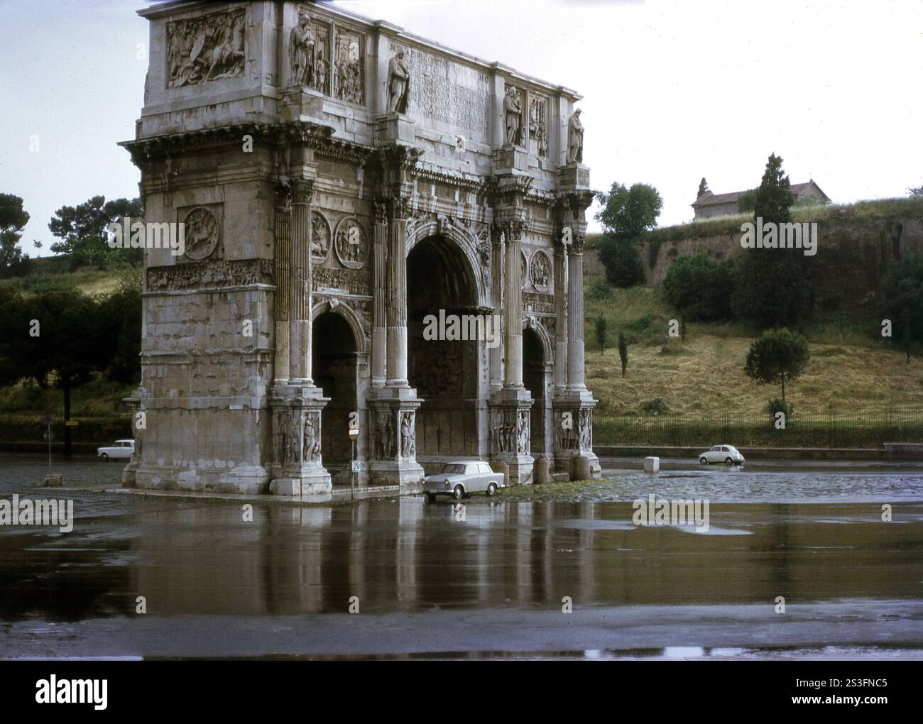 1970, a car of the era parked by The Arch Of Constantine, a triple arch ...