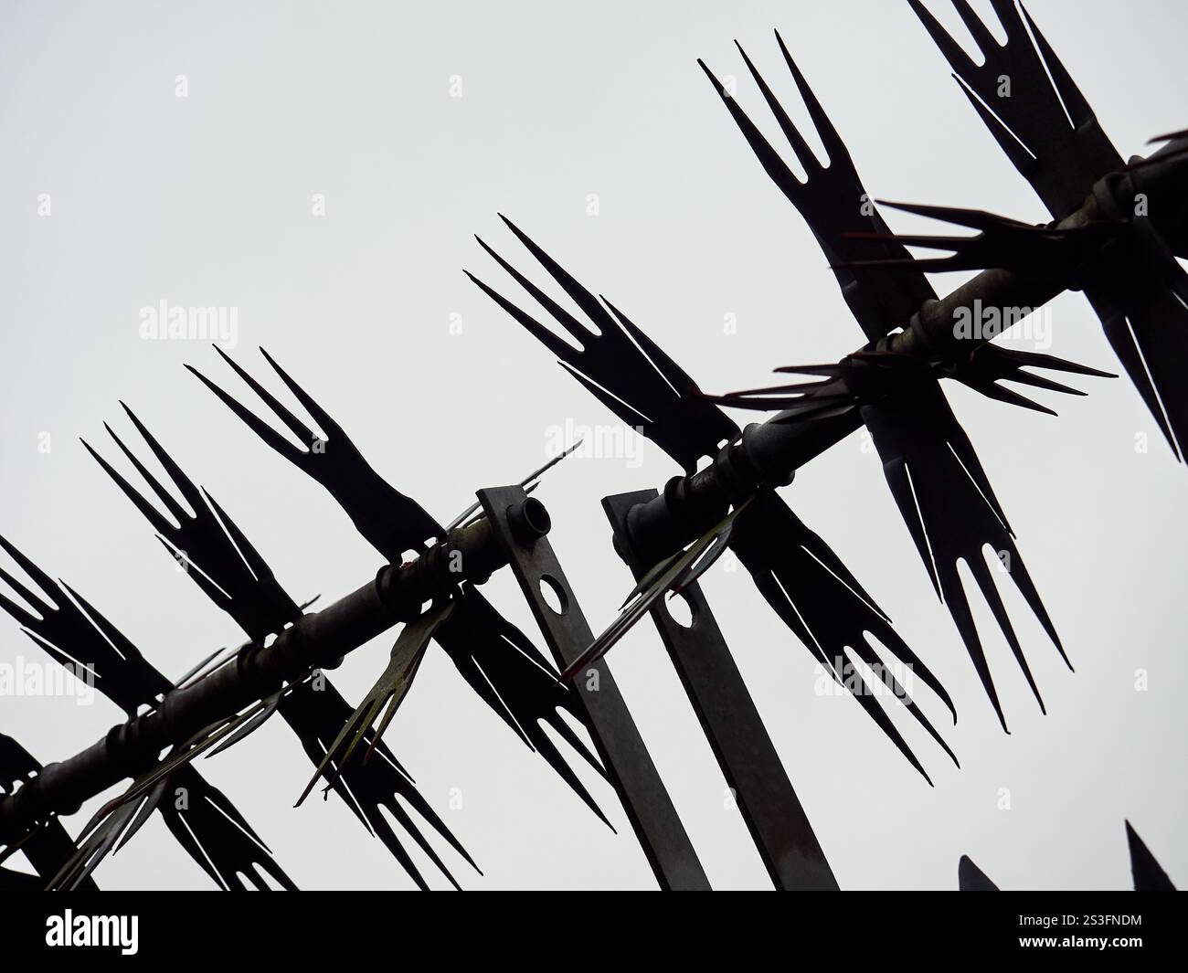 Sharp metal spikes line a commercial building rooftop, silhouetted ...