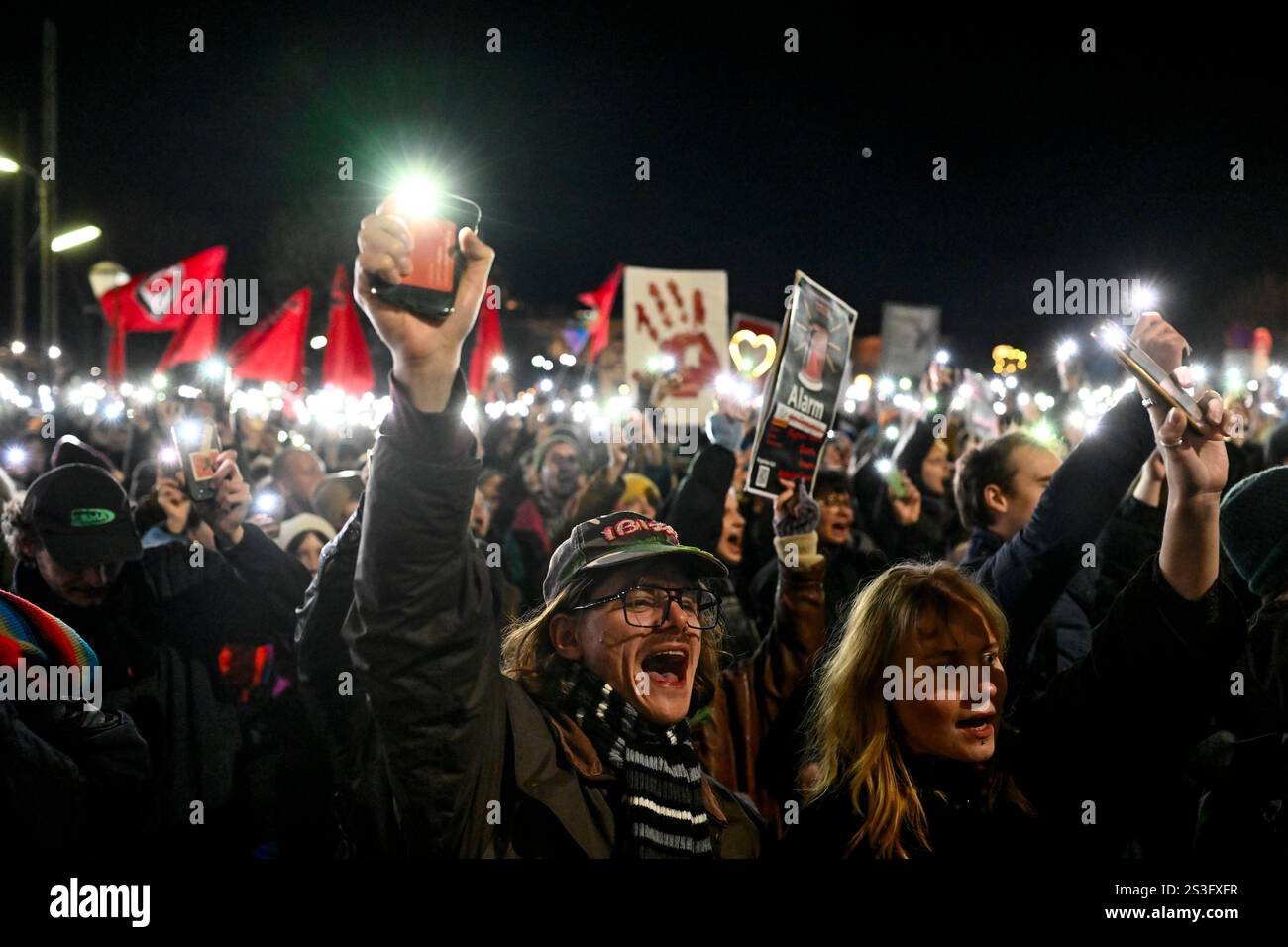 People hold up their cell phones as they during a protest against the ...