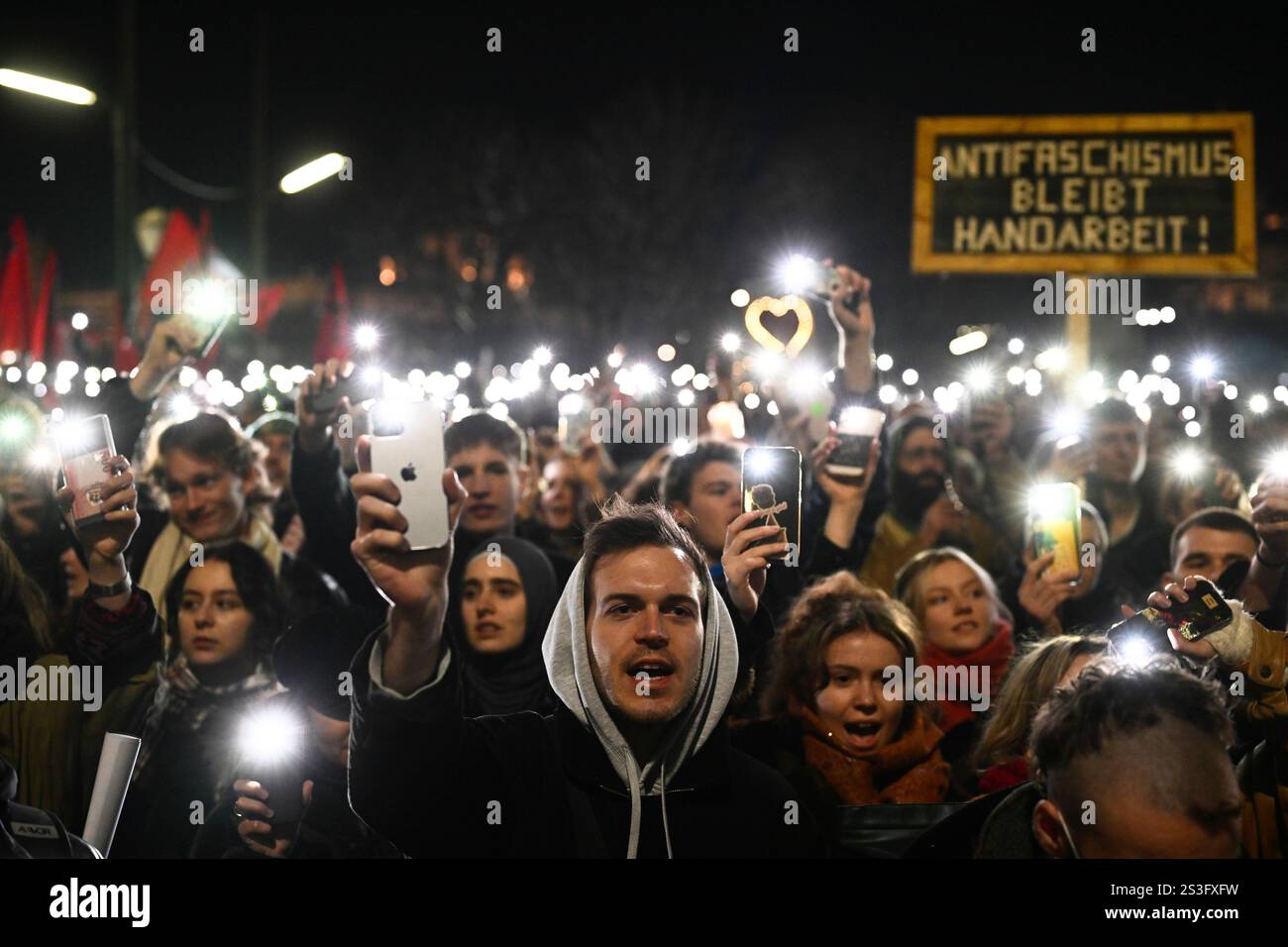 People hold up their cell phones as they during a protest against the ...