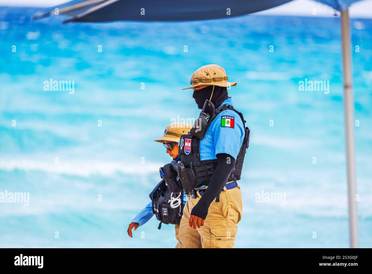 Mexican police officers patrolling Caribbean beach near turquoise sea ...