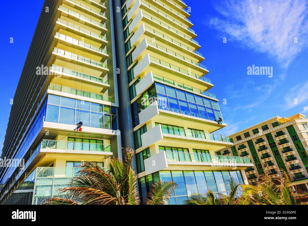 High-rise hotel building with window cleaners working under clear blue ...