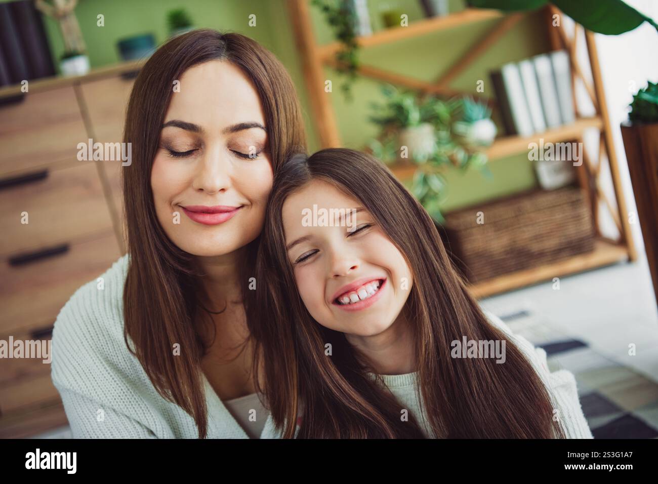 Happy young mother and daughter in a cozy living room, embracing the joy of motherhood and ...