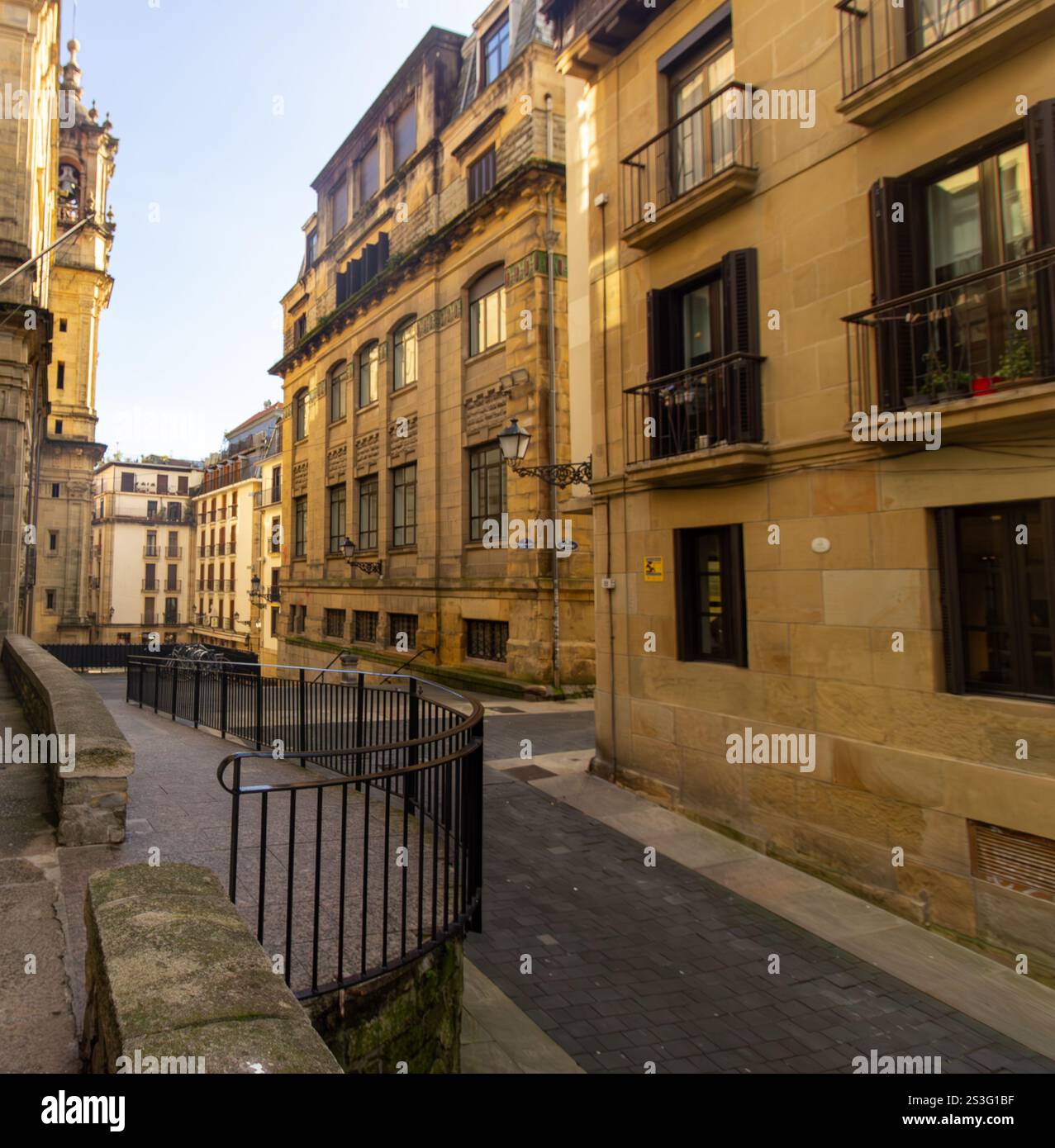 Narrow alley with traditional buildings, balconies, and street lamps in ...