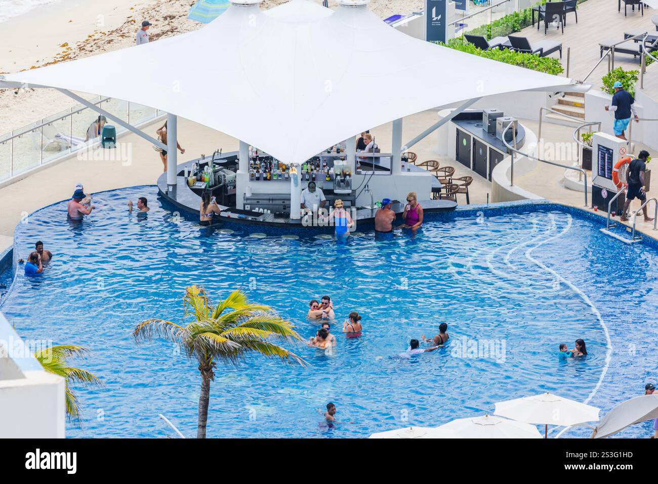 Resort swimming pool with swim-up bar and people relaxing in water ...