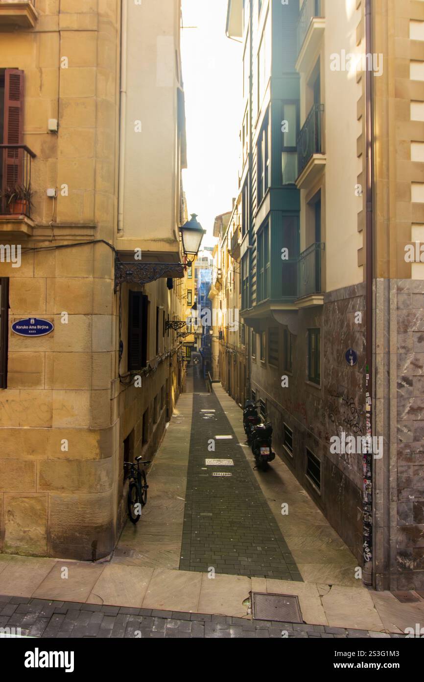 Narrow alley with traditional buildings, balconies, and street lamps in ...