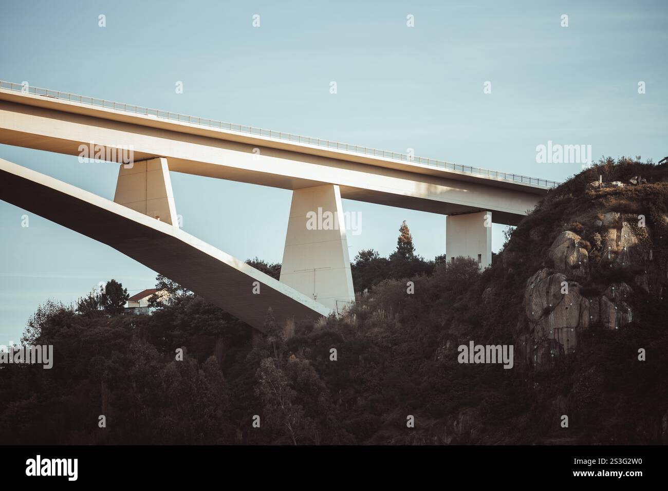 Modern concrete bridge with large angular supports spanning a lush ...