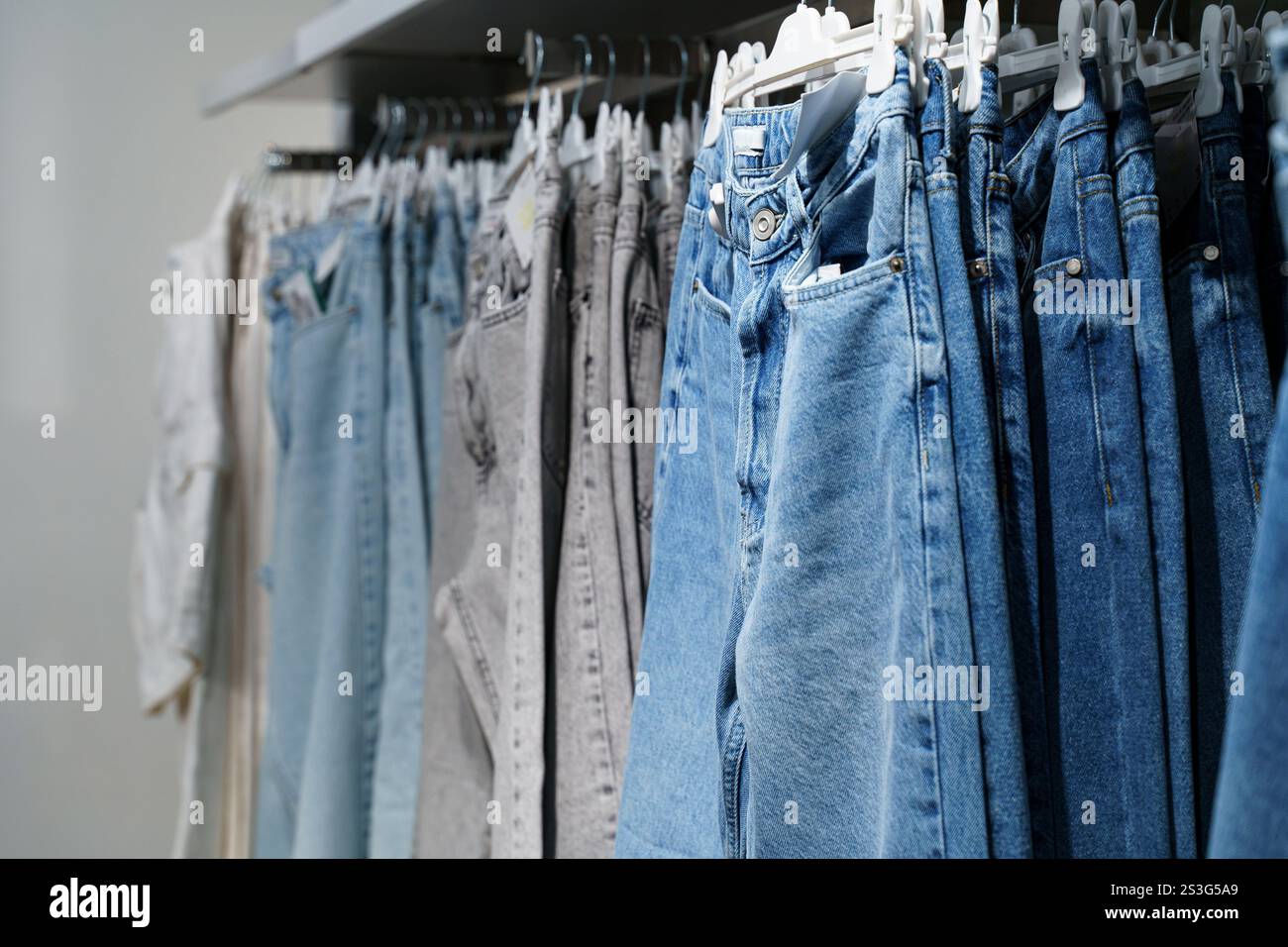 Various styles of denim jeans are showcased on hangers in a ...
