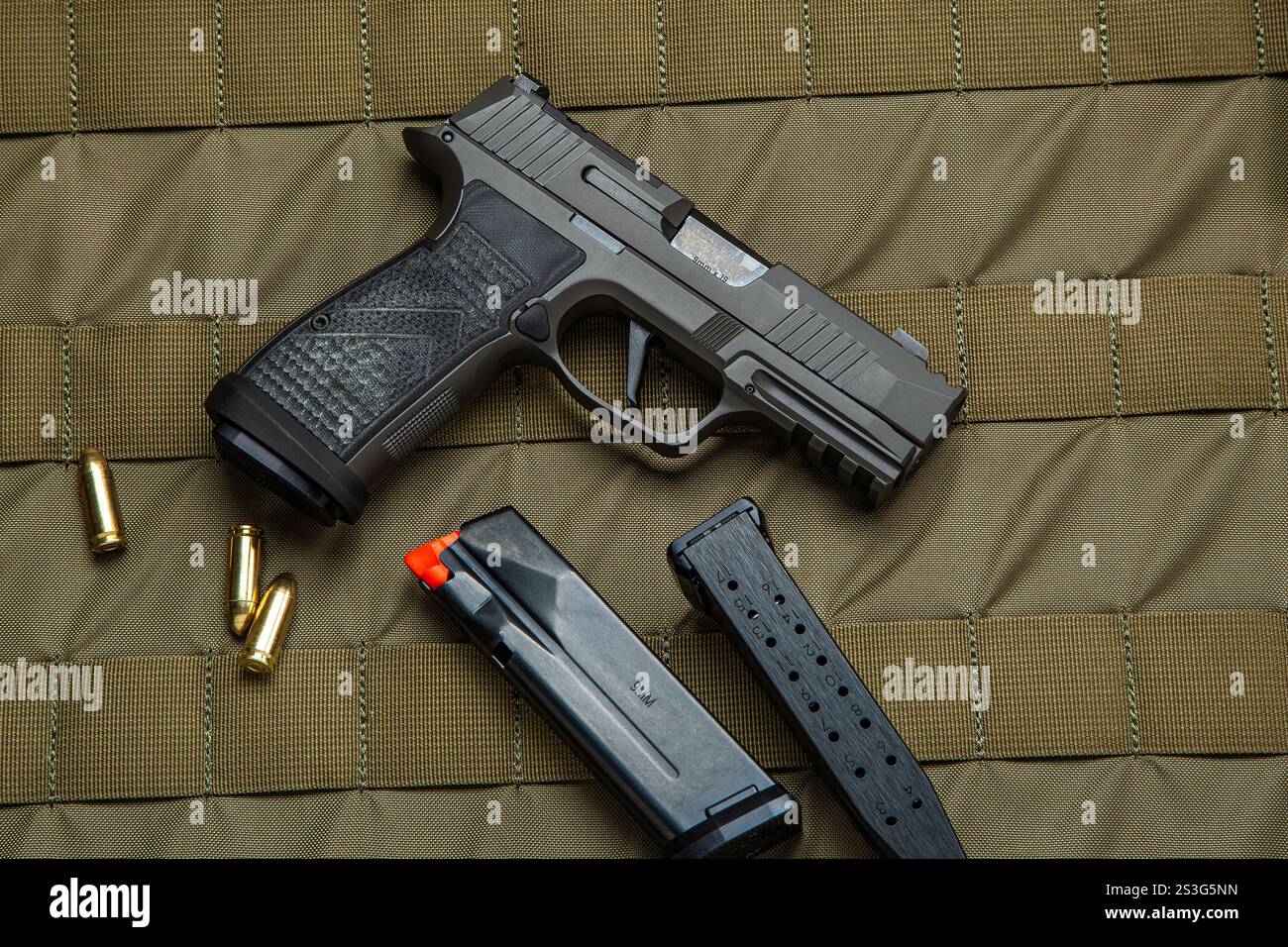 A black handgun with a textured grip, two magazines, and four bullets ...