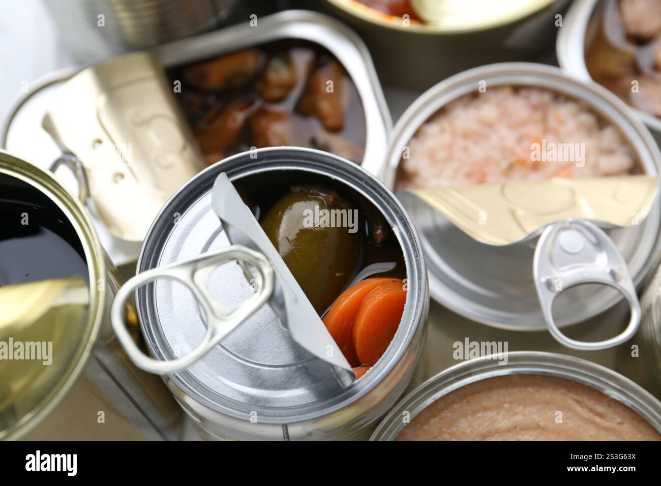 Open tin cans with different preserved products on table, above view ...
