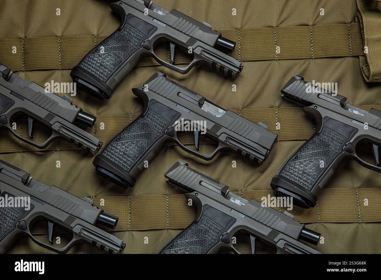 A collection of black handguns with textured grips are arranged on a ...