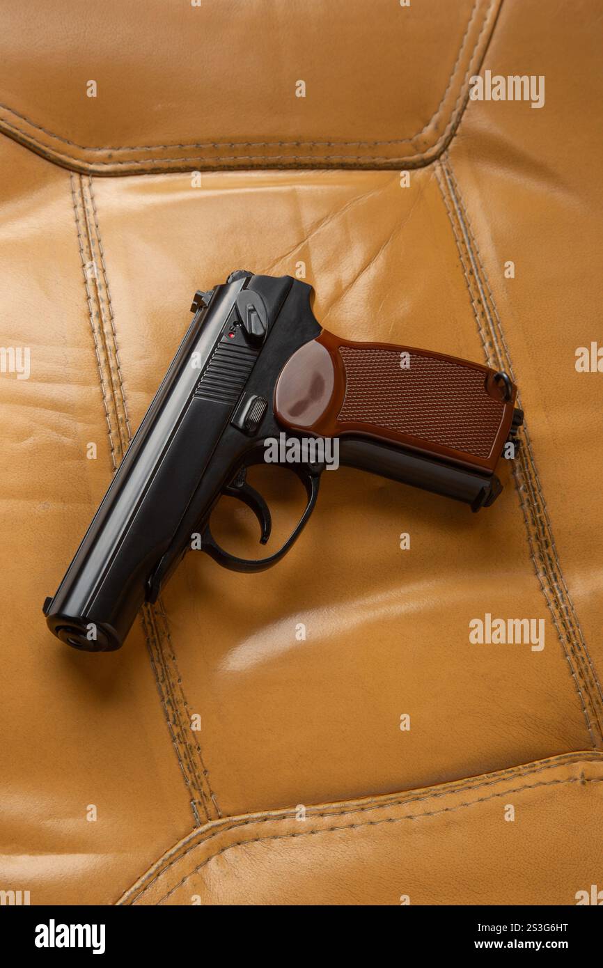 A realistic air pistol replica of an original firearm, placed on a tan ...