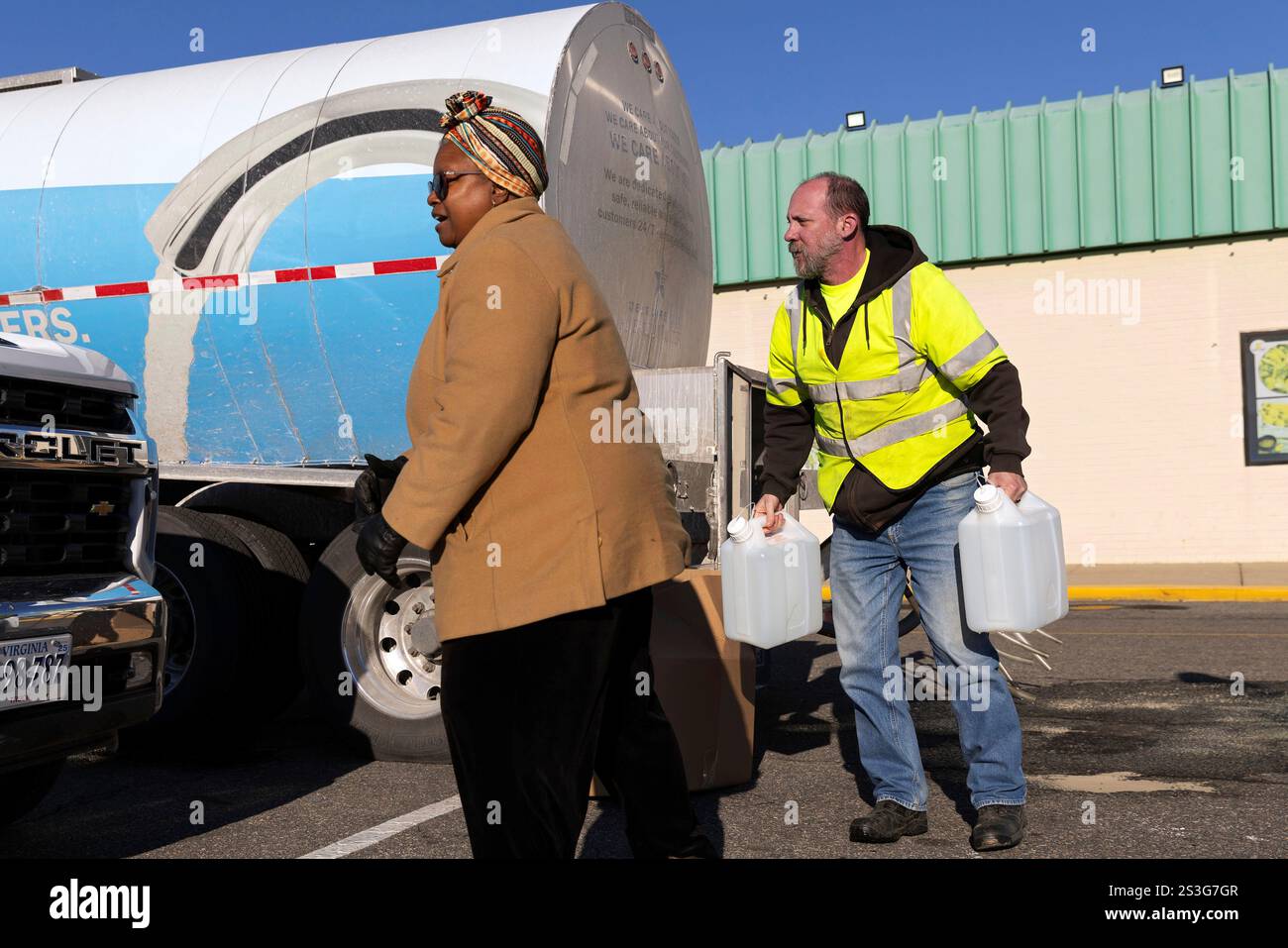 Adam Guay carries jugs of water for Theresa Slayton from a tank truck ...