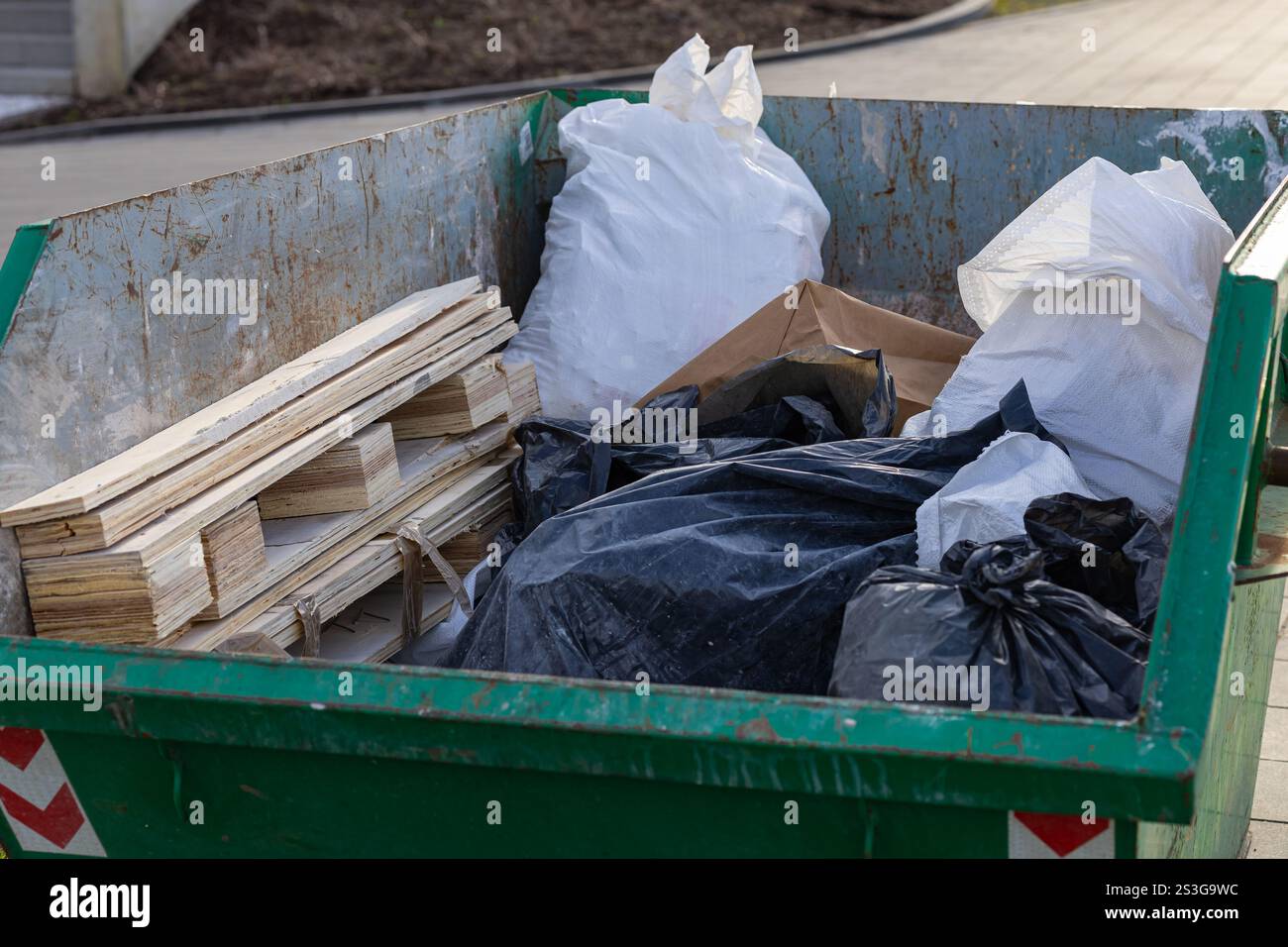 Construction waste in a dumpster on construction site with wood planks ...