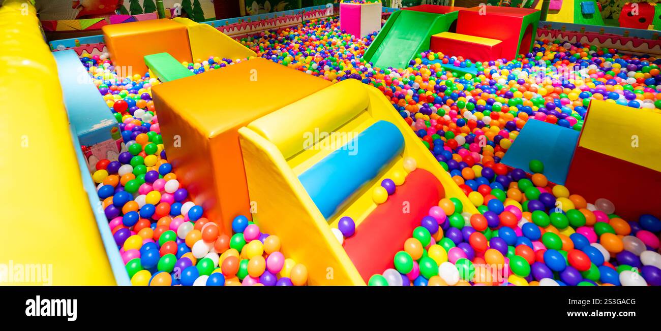 A colorful ball pit with soft play structures in a vibrant indoor ...