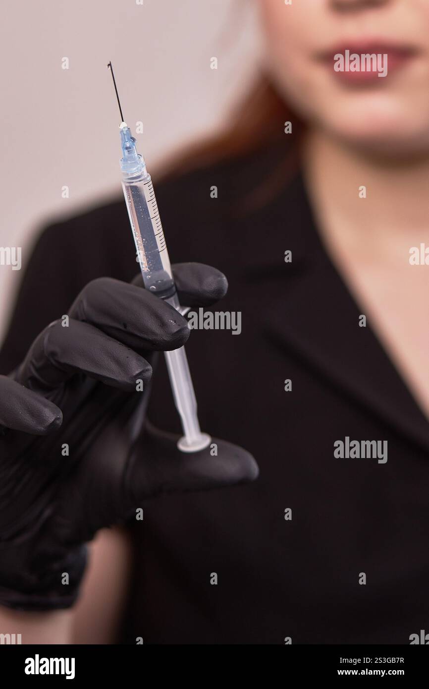 Hand in black glove holding syringe with blue liquid, medical injection ...