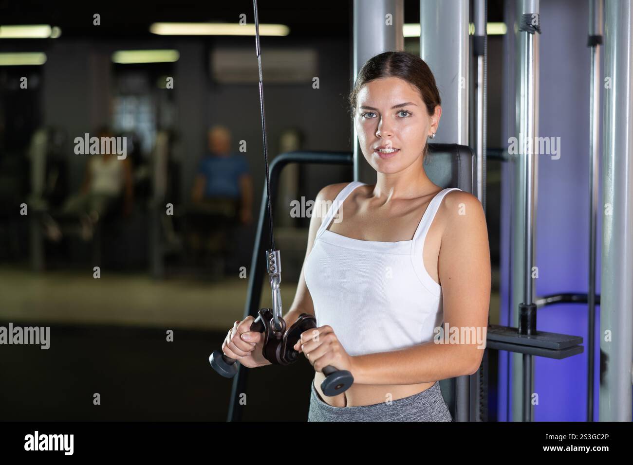 Athletic girl work out muscles of arms and shoulders on rope loop ...