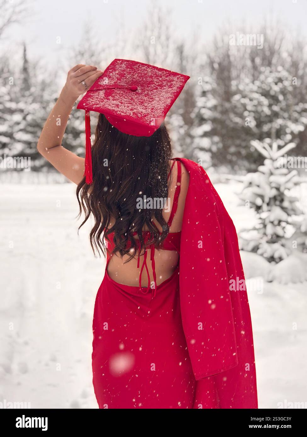 Graduating girl with long brunette hair wearing red cap, dress and ...
