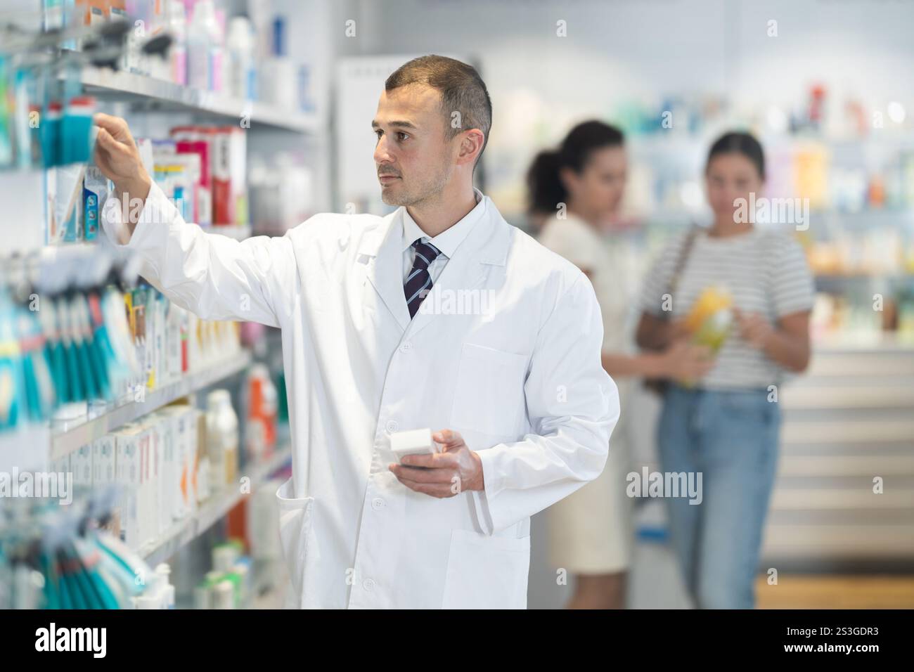 Positive male pharmacist in medical uniform posing while working in ...