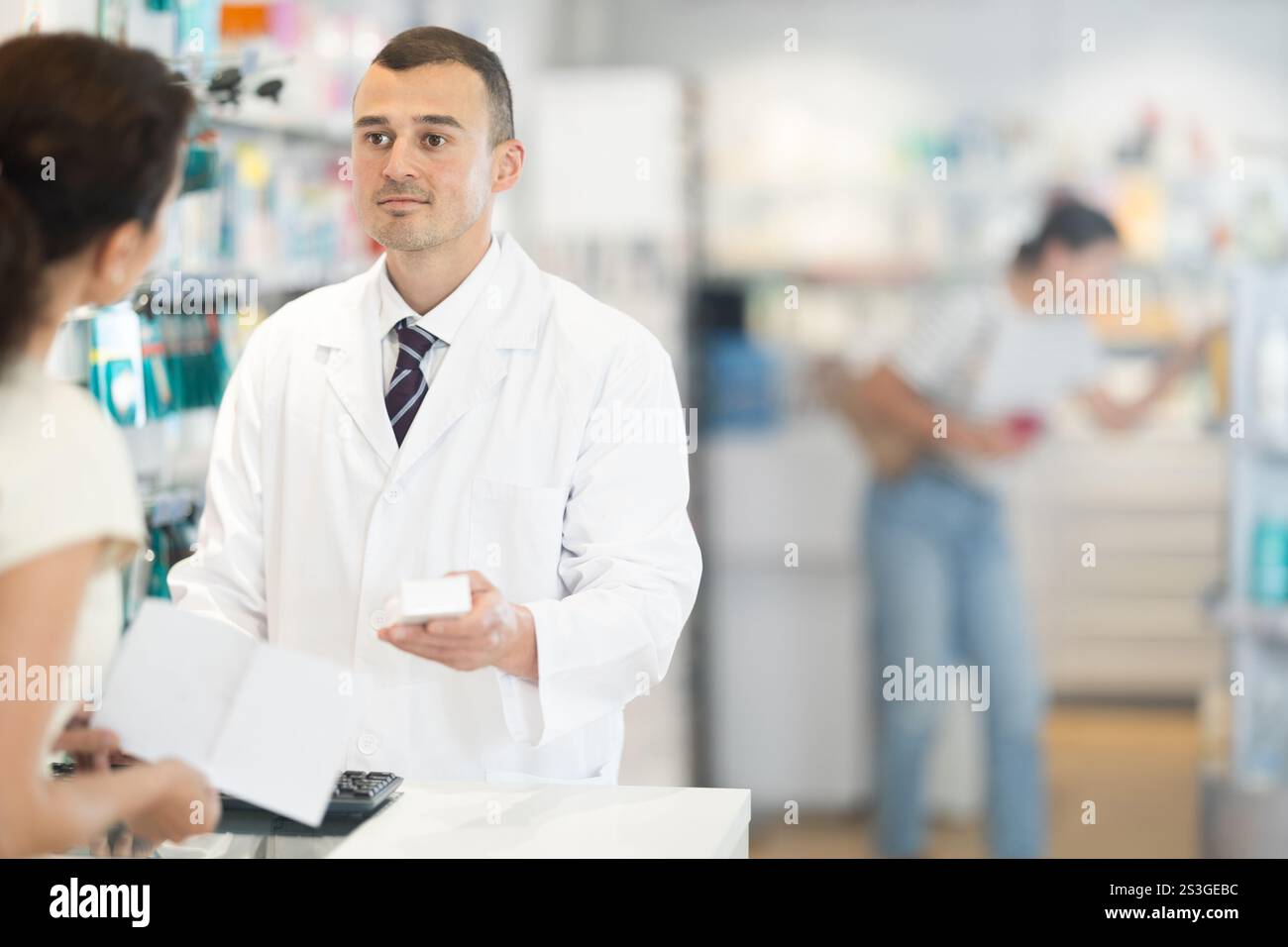Male pharmacist speaking to woman customer buying medical preparation ...