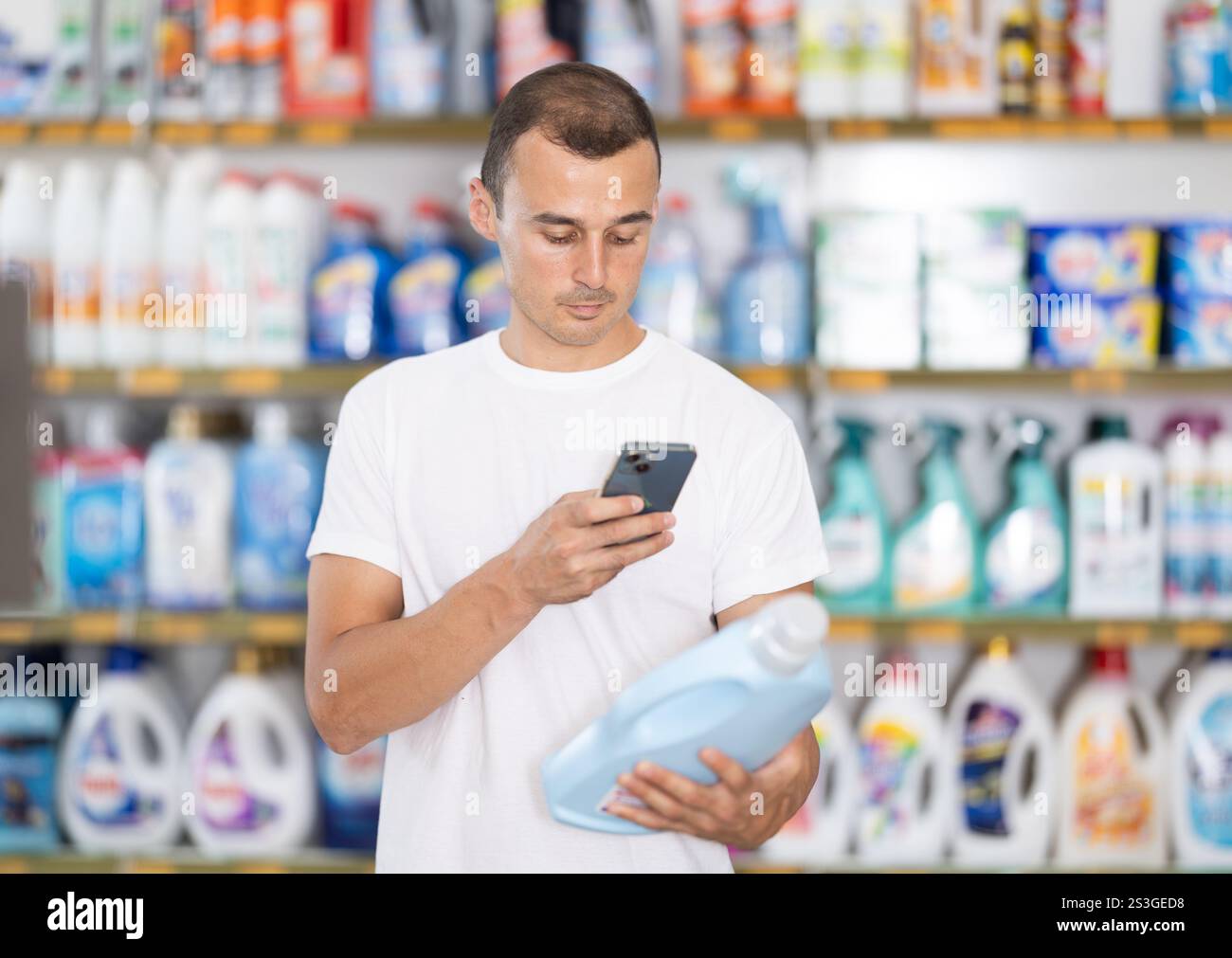Young man scanning qr code for laundry detergent Stock Photo - Alamy