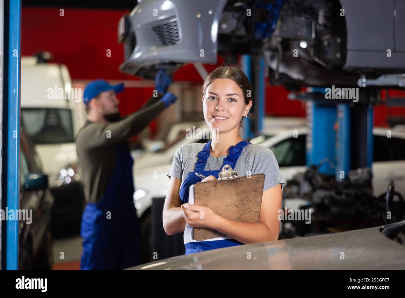 Female car service worker keeps records of work performed by auto ...