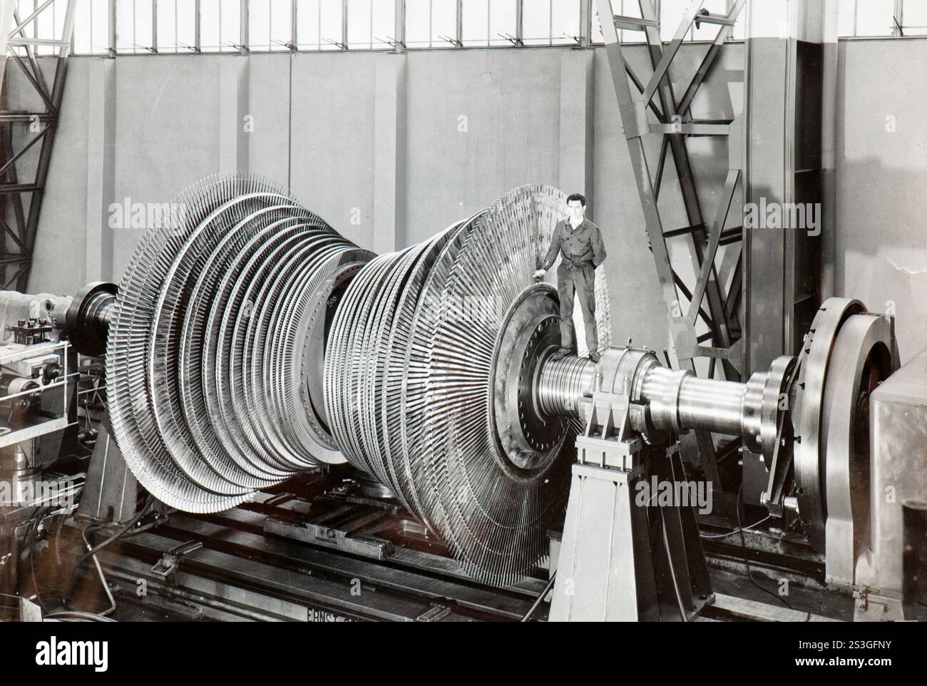 A worker poses on top a huge gas turbine shaft inside the production ...