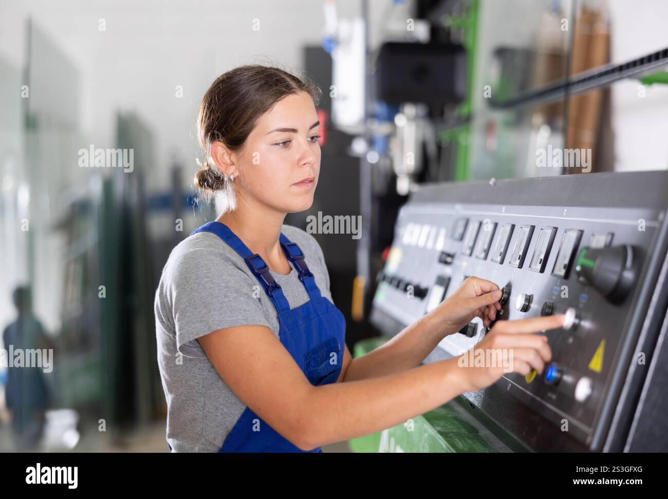 Glass factory worker at workplace with control panel, controlling ...
