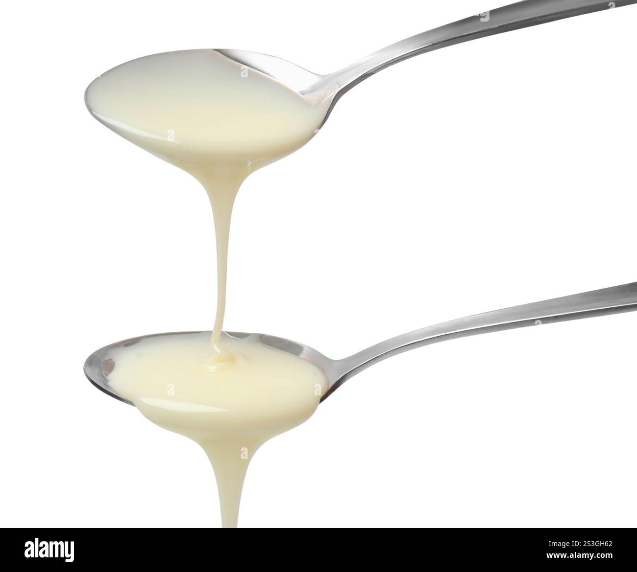 Condensed milk flowing down from spoons isolated on white Stock Photo ...