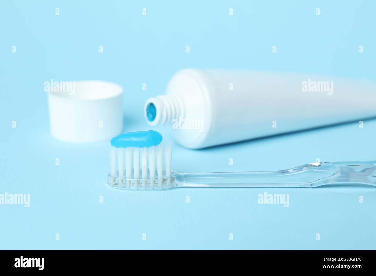 Toothbrush with toothpaste and tube on light blue background, closeup ...