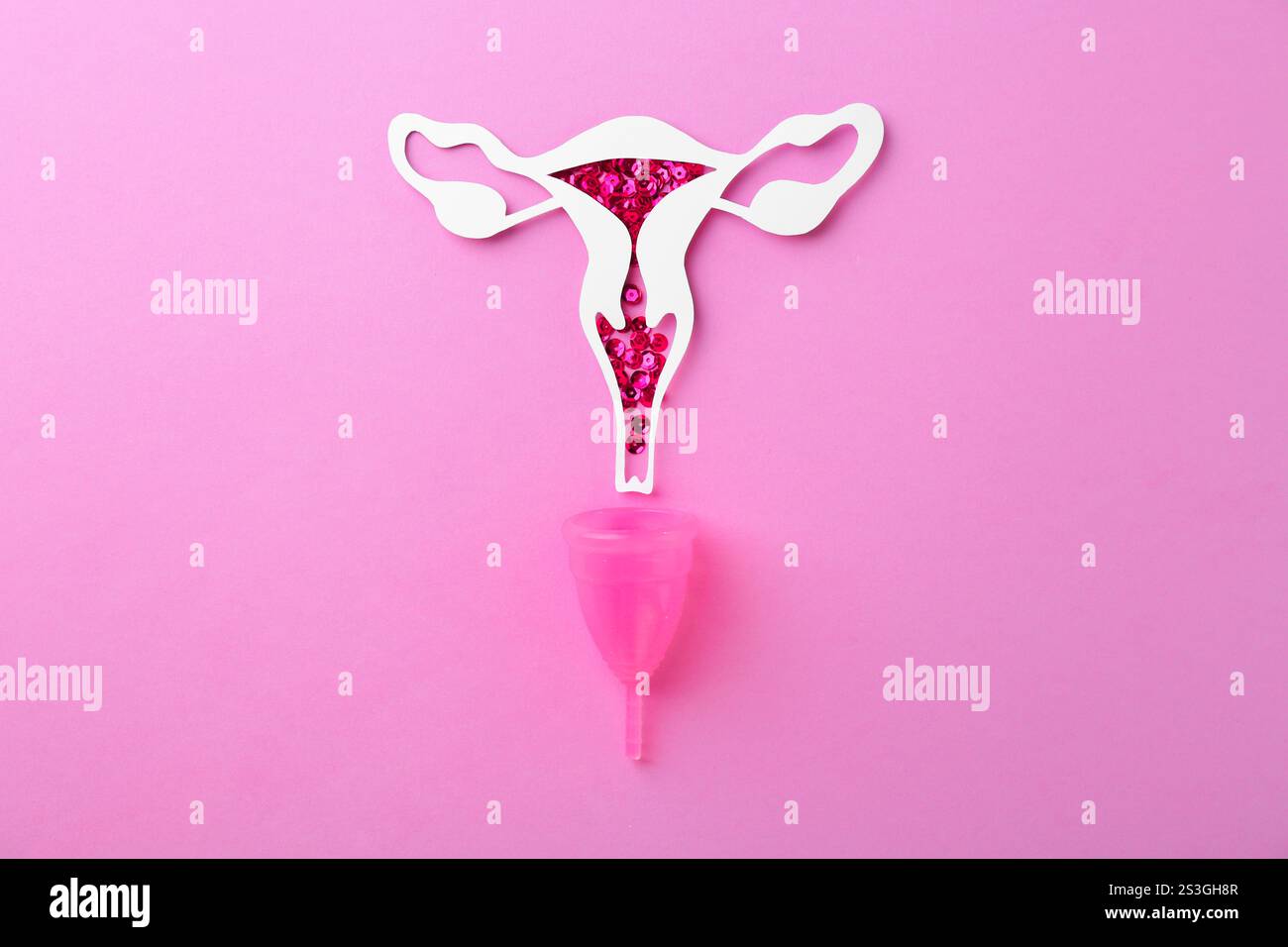 Paper uterus with sequins and menstrual cup on violet background, top ...