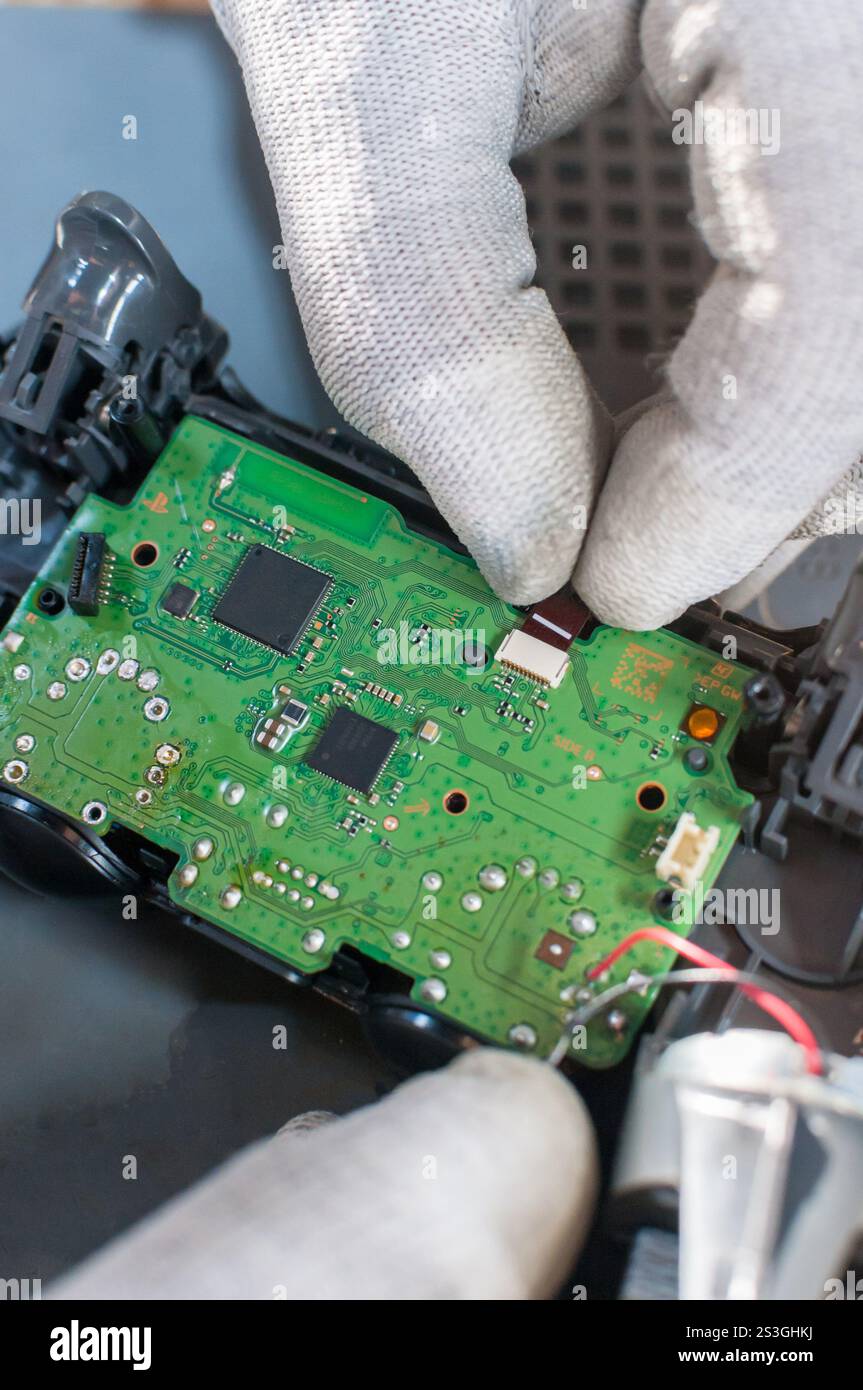 Hand with glove plugging some connection from a video game controller ...