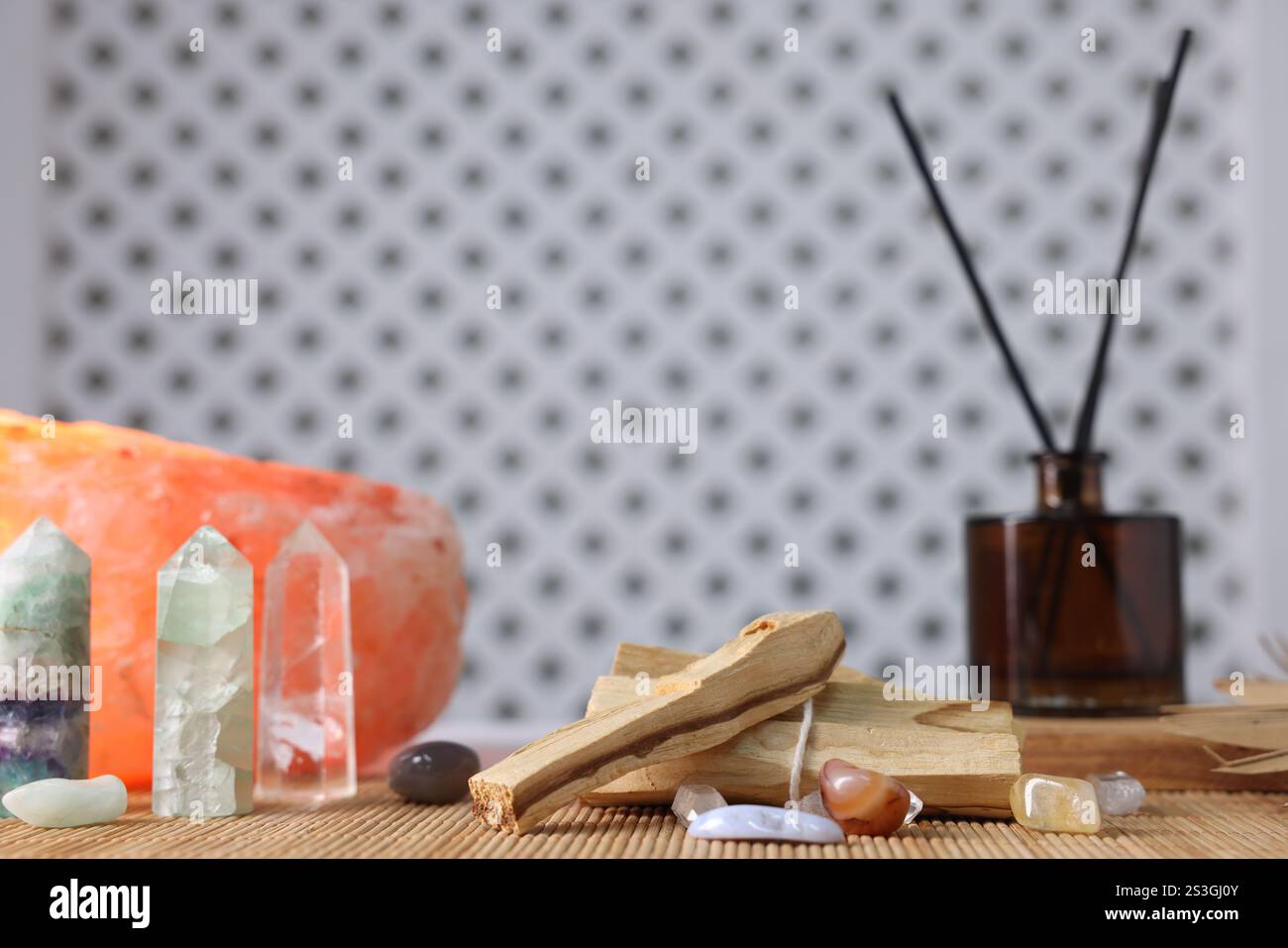 Palo santo sticks, gemstones and reed diffuser on bamboo mat, closeup ...