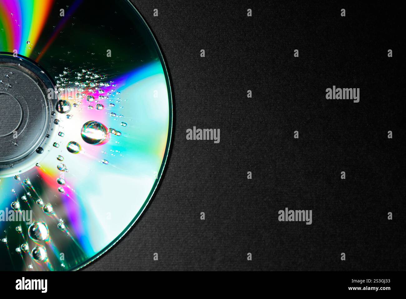Compact disc with drops on black background, top view. Space for text ...