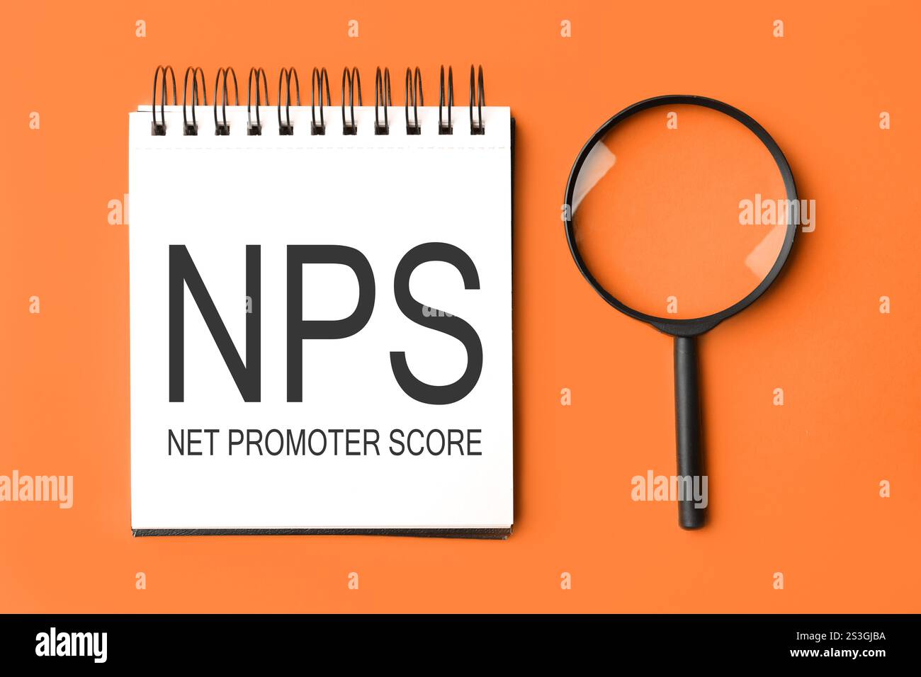 NPS (net promoter score) in notebook and magnifying glass on orange ...