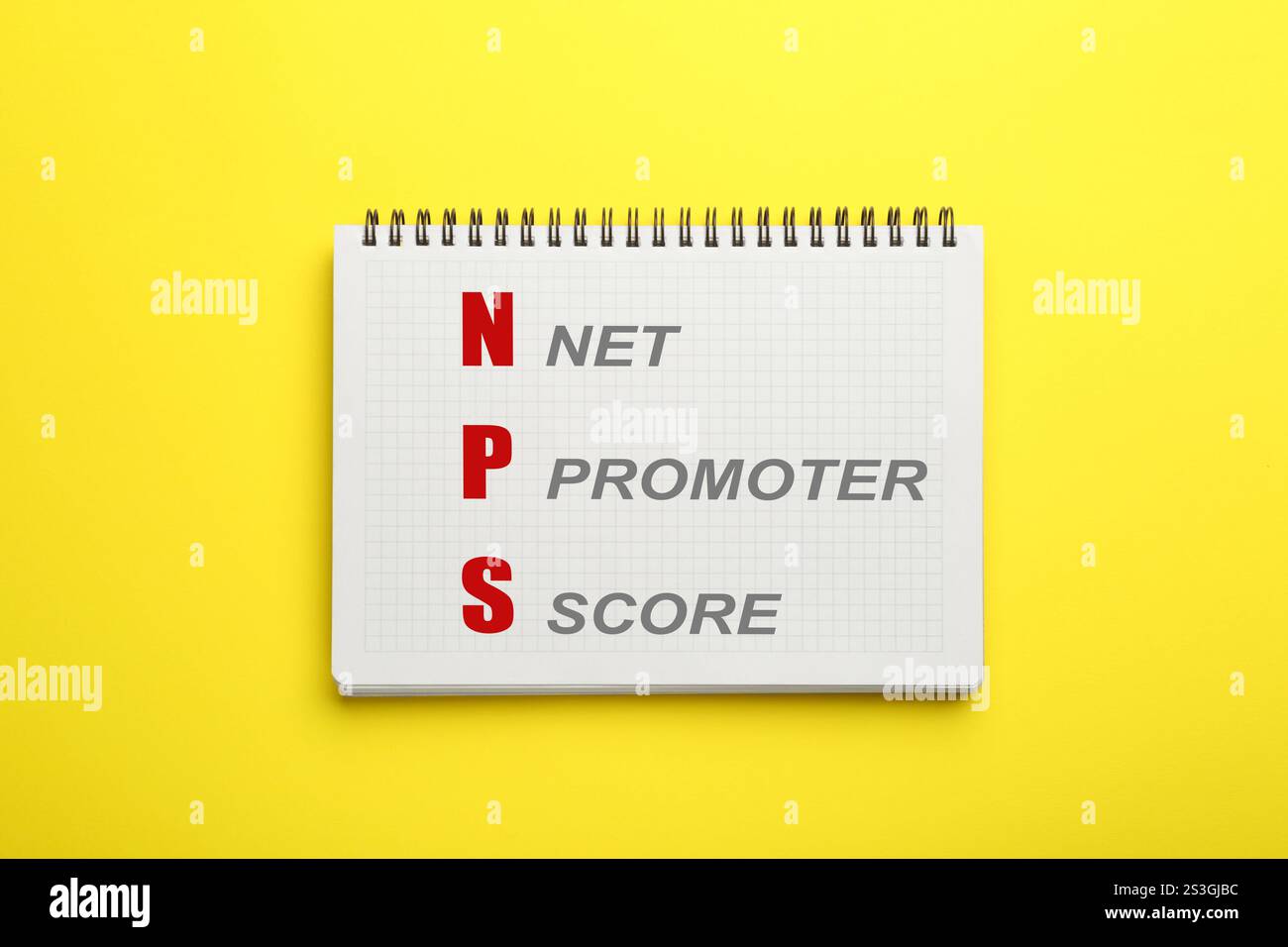 NPS (net promoter score) in notebook on yellow background, top view ...
