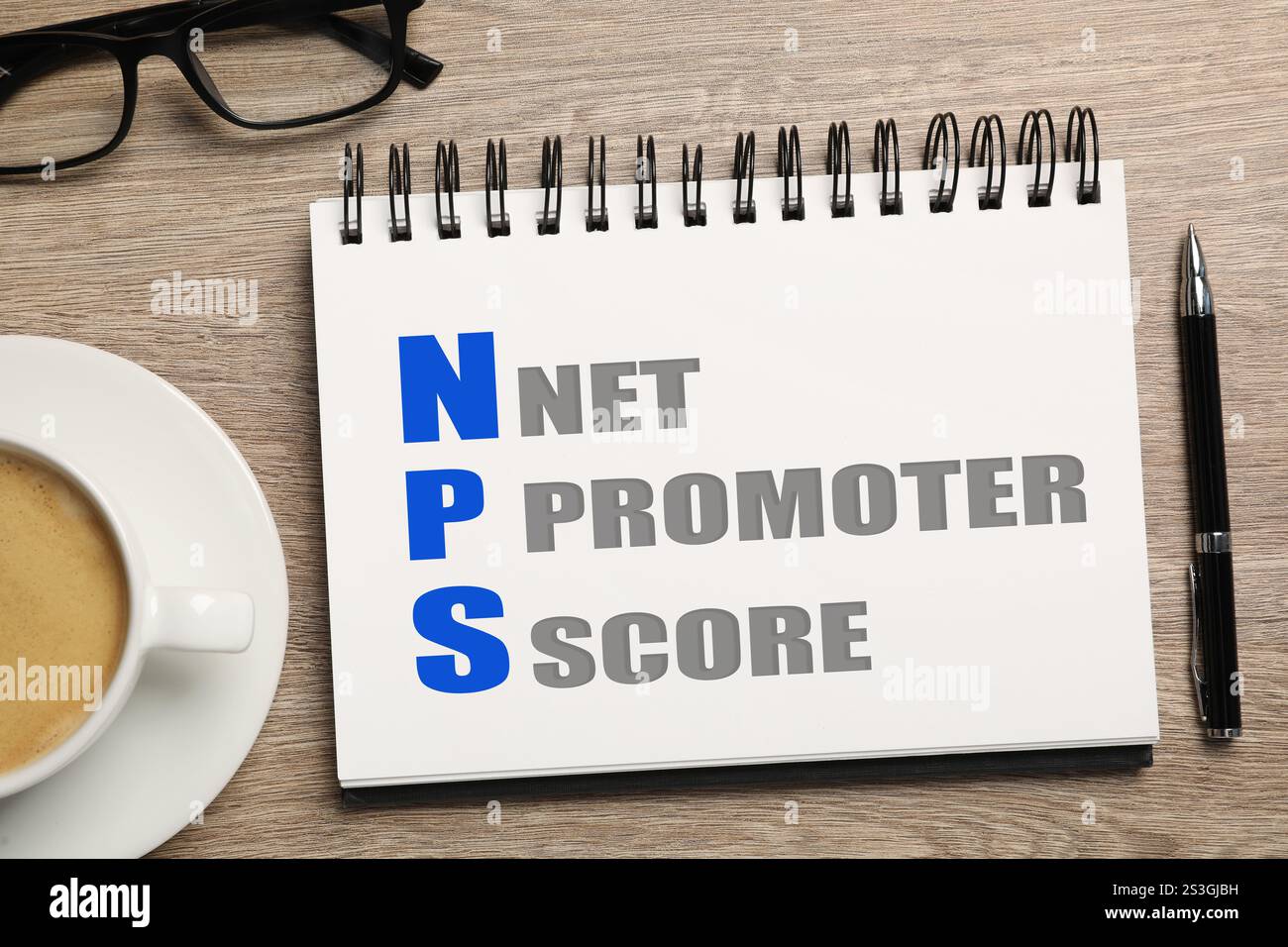 NPS (net promoter score) in notebook, pen, glasses and coffee on wooden ...