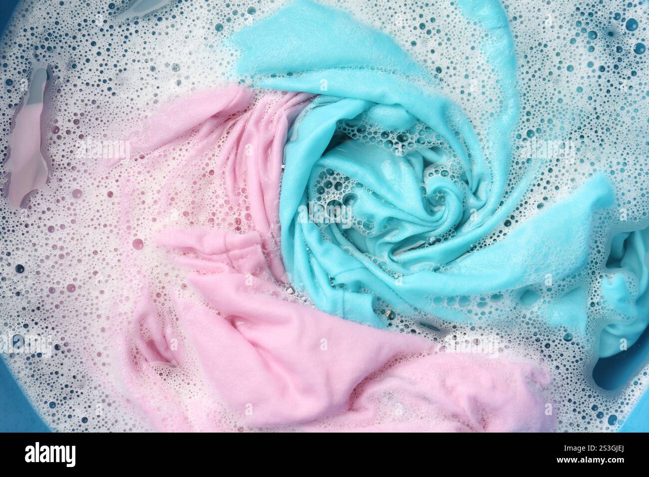 Colorful clothes soaked in water before washing, top view Stock Photo ...