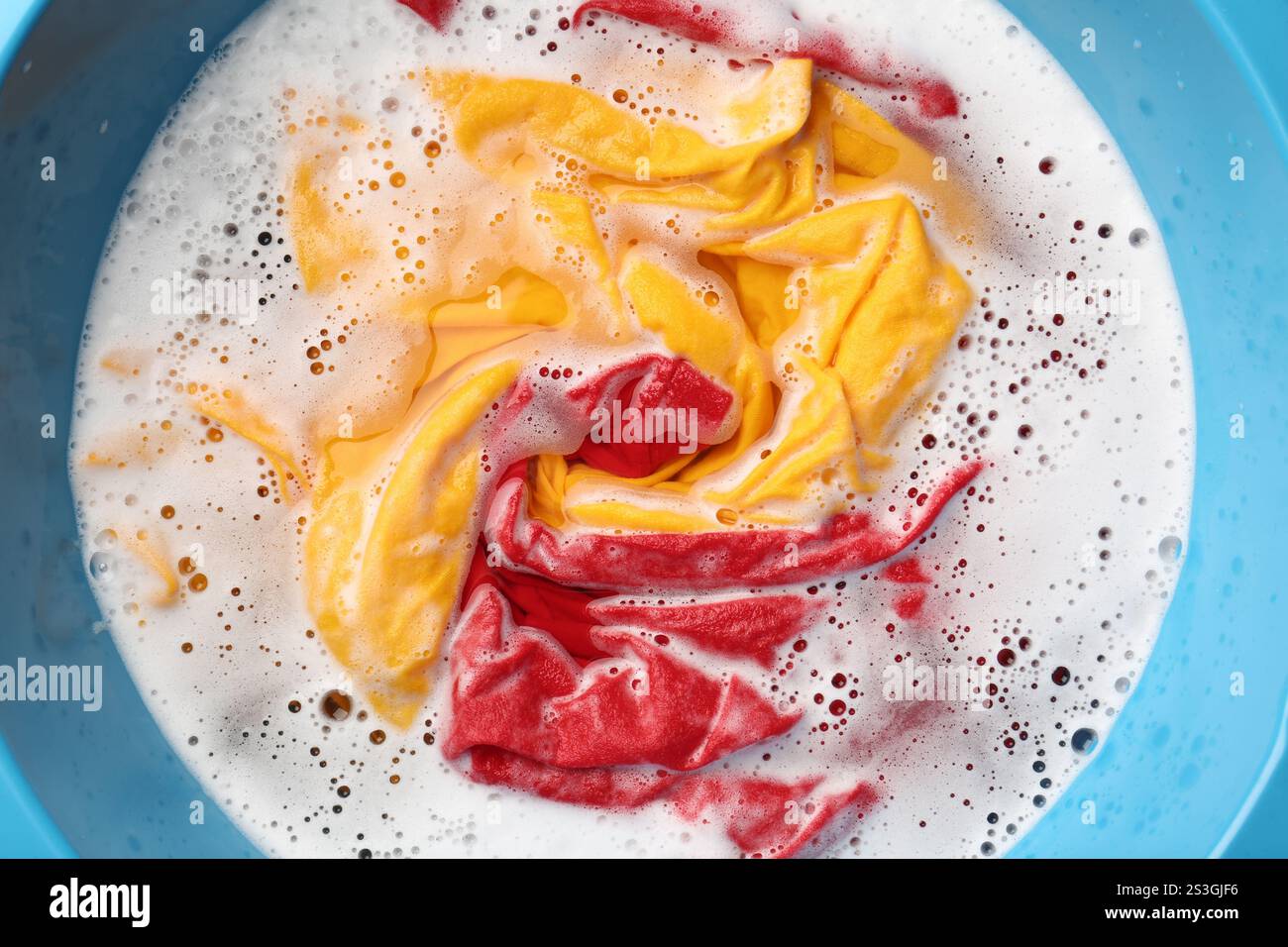 Colorful clothes soaked in water before washing, top view Stock Photo ...