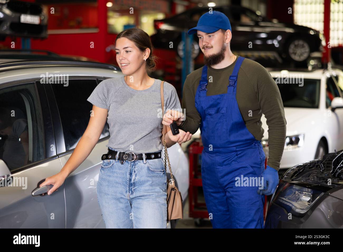 Happy girl with near her car being repaired. Auto mechanic give her car ...