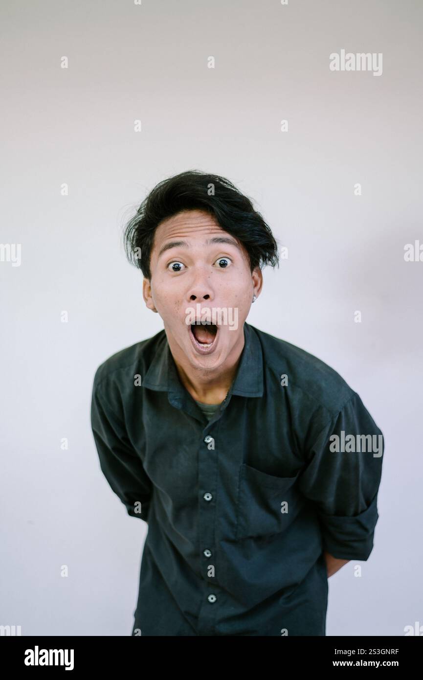 A young man in a black shirt with a shocked expression, wide eyes, and ...