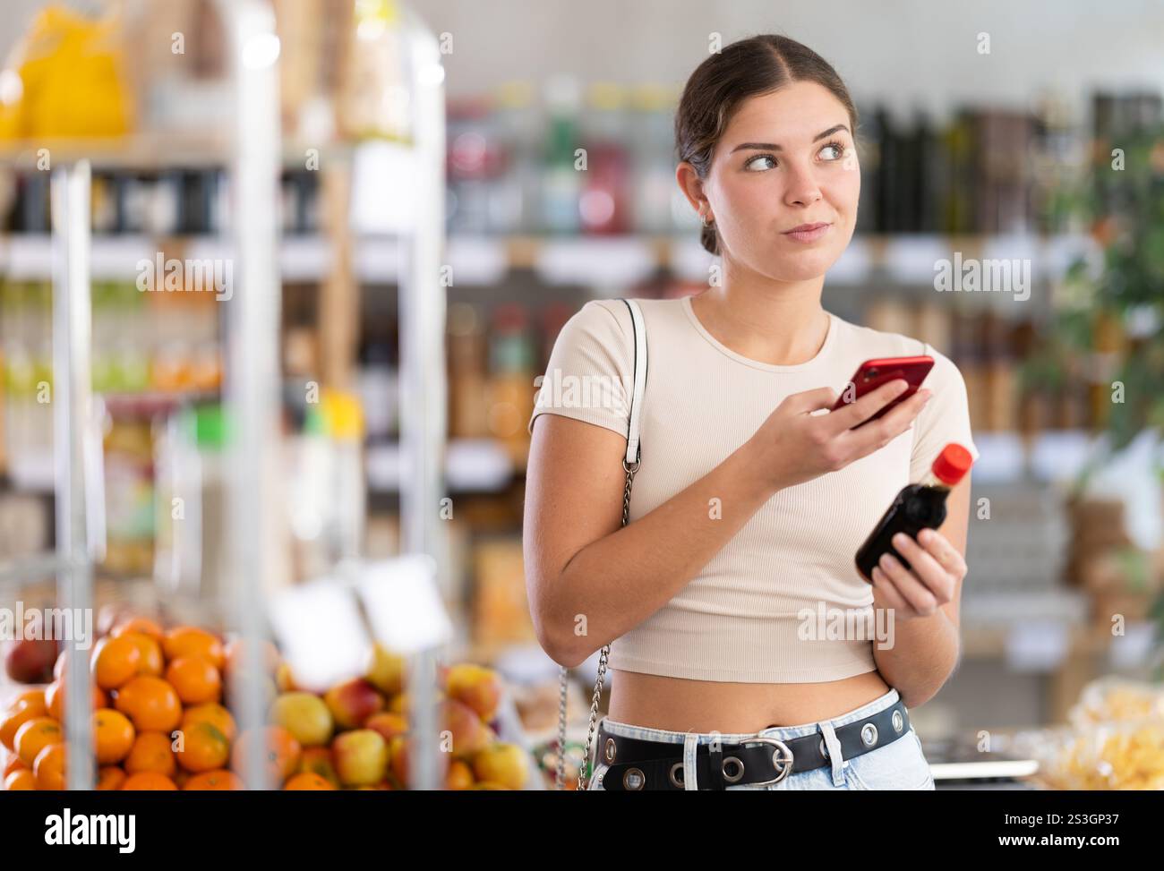 Young woman customer at shop scans QR code on soy sauce bottle using ...