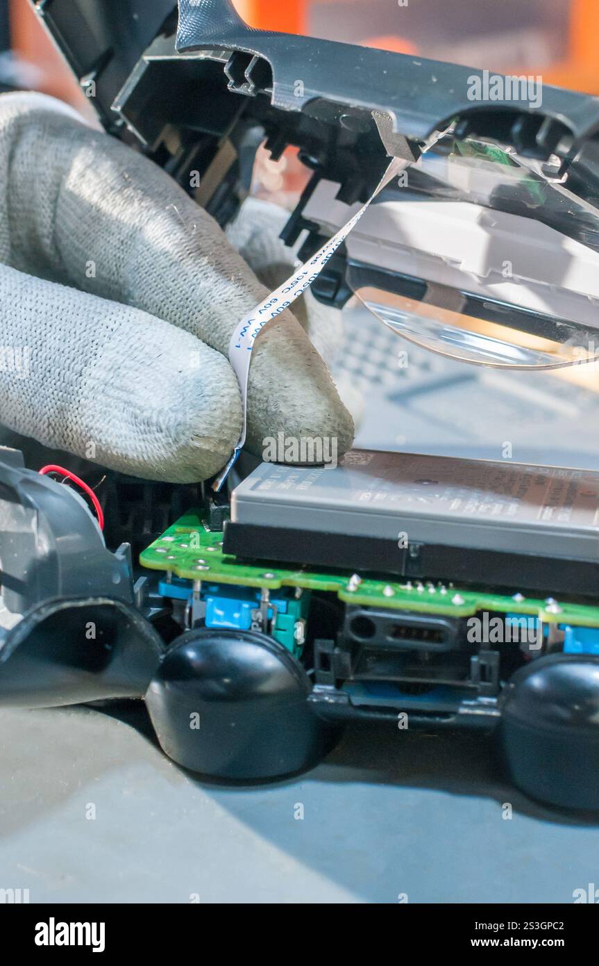 Hand with glove plugging some connection from a video game controller ...
