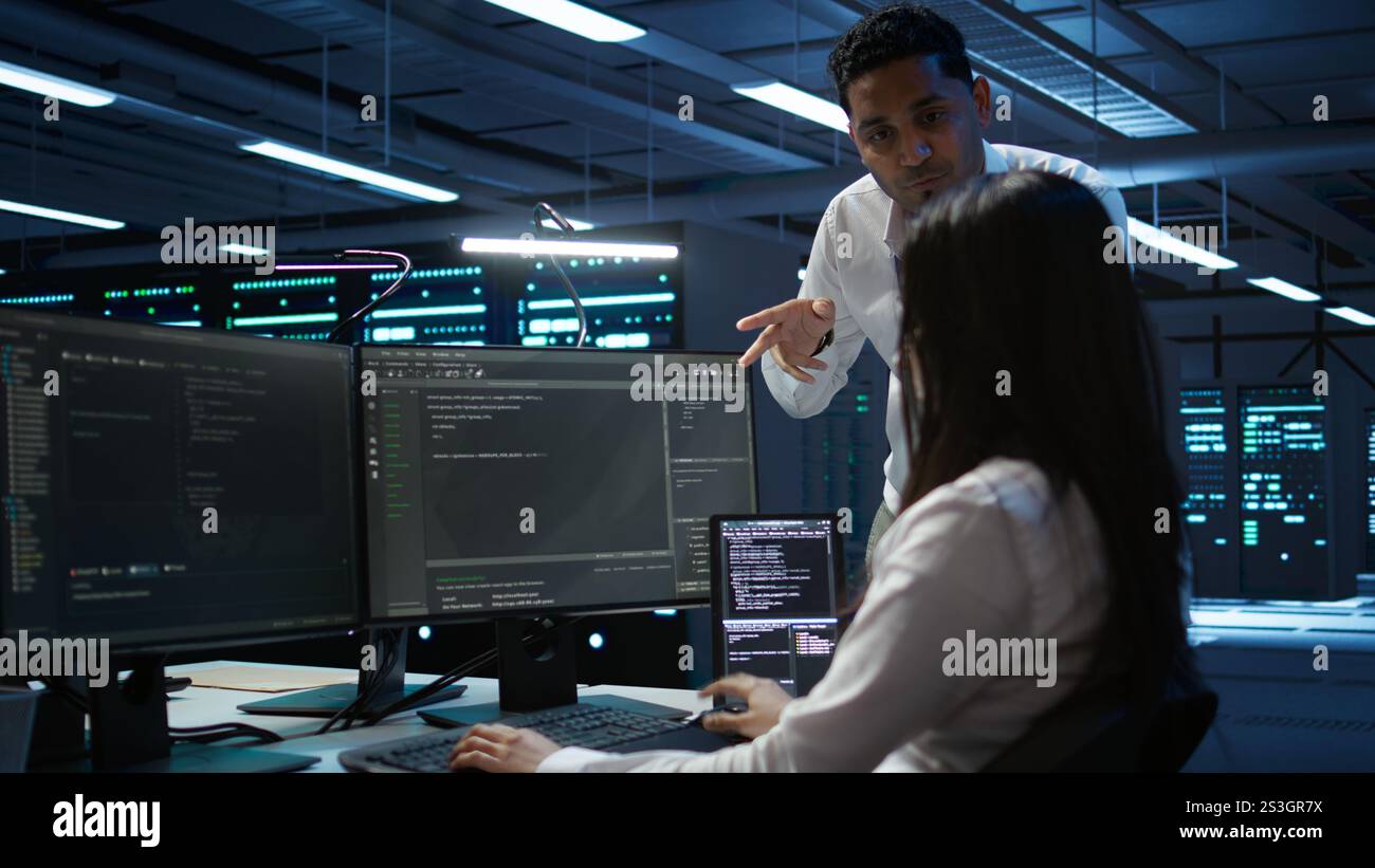 Engineering team colleagues in data center managing gear energy consumption, working on PC ...