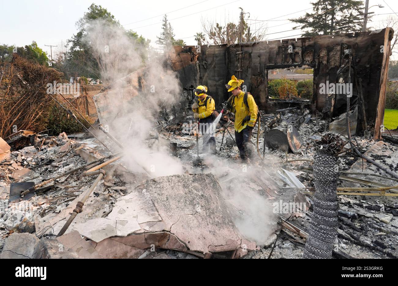 Firefighters extinguish burning embers at a house on Santa Rosa Avenue ...