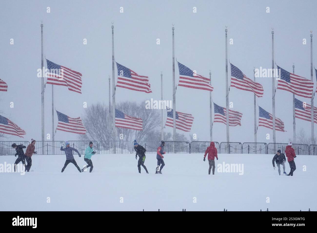 People engage in a snowball fight as U.S. flags along the base of the ...