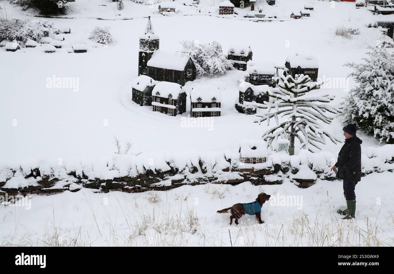 A man walks his dog in the heavy snow past miniature landmark models in ...