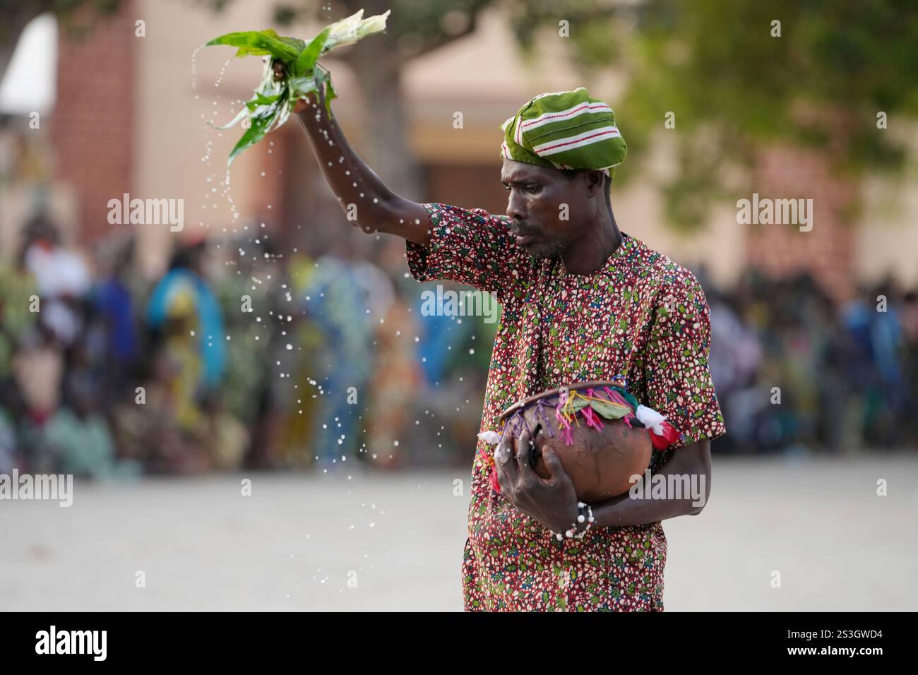 A man sprinkles water as Zangbeto masquerades the traditional Voodoo ...