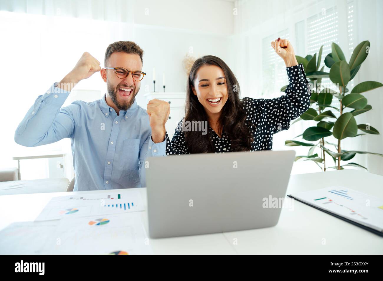Joyful business team celebrating success at a desk, multiracial man and ...